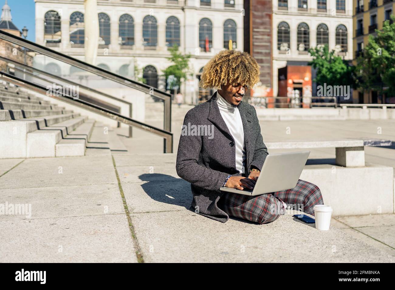 Handsome smart african man talking using a computer at the street ...