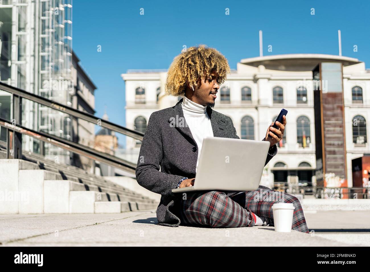Handsome smart african man talking using a computer at the street ...