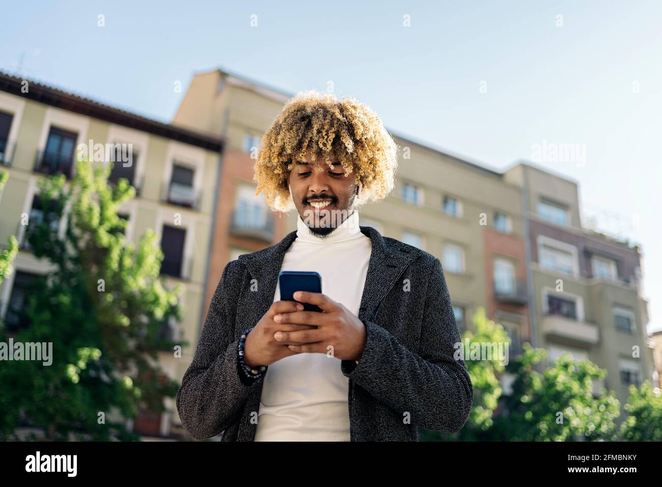 Handsome smart african man typing mobile phone at the street ...