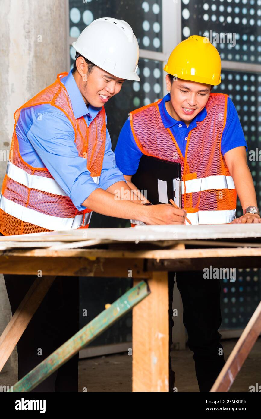 Chinese architect and supervisor point on building site on a ...