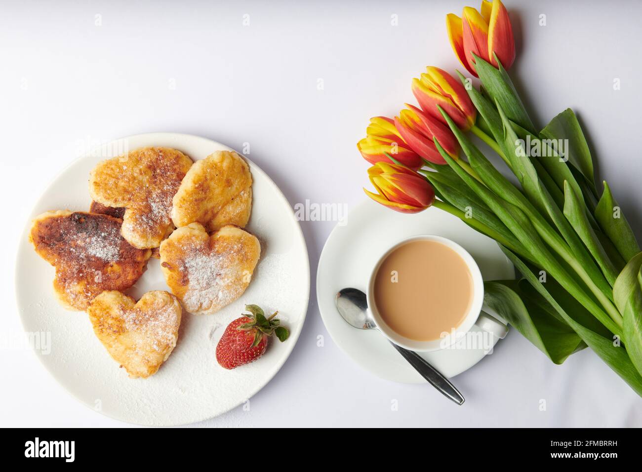a cup of tea with a spoon stand on a white background and a bouquet ...