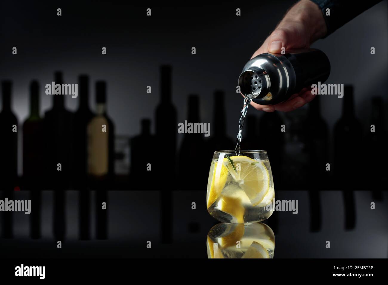 Cocktail "Gin-tonic" on a black reflective background. The bartender ...