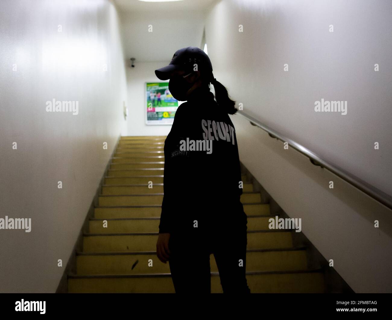 A rear view of a female security guard in uniform patrolling in a ...
