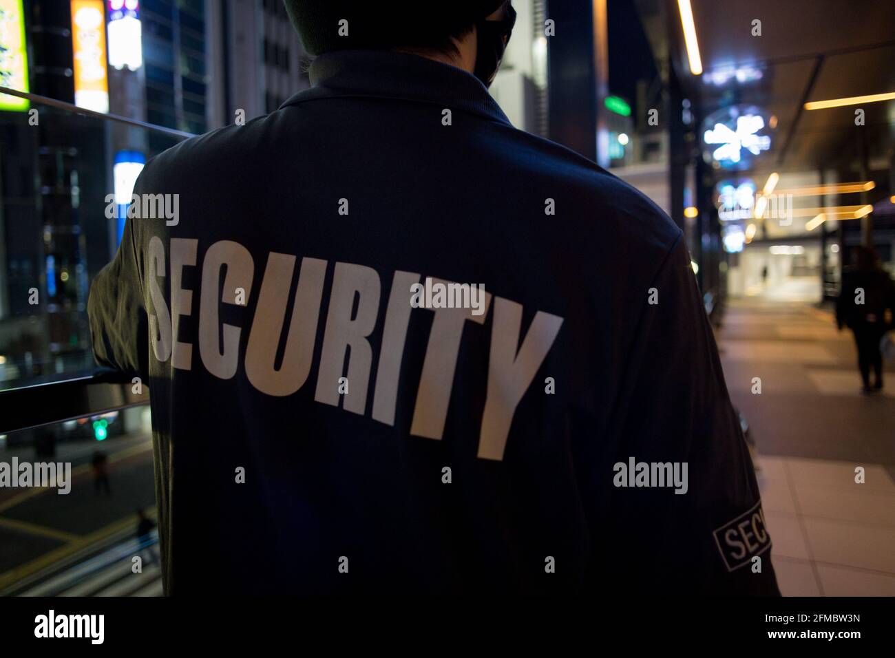 A rear view of a security guard walking through the street of the big ...