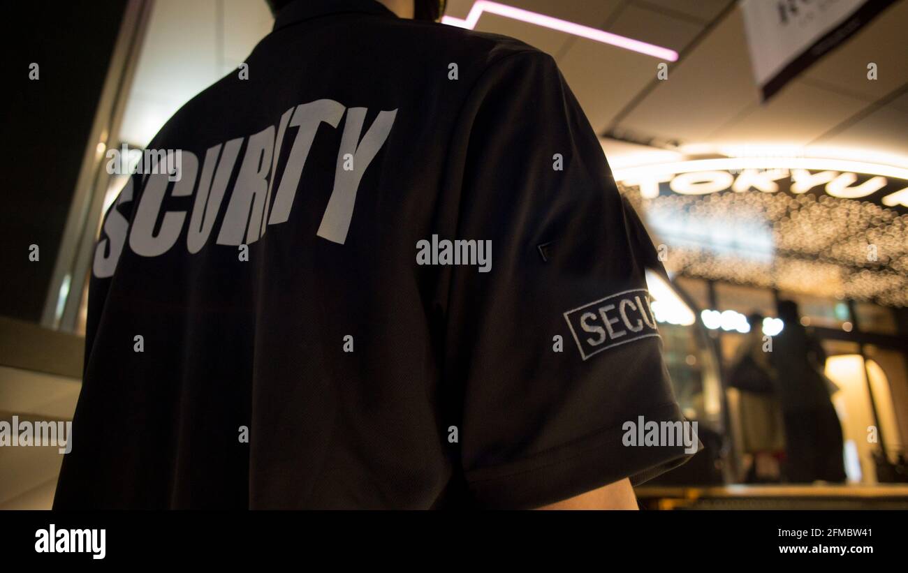 A rear view of a security guard walking through the street of the big ...