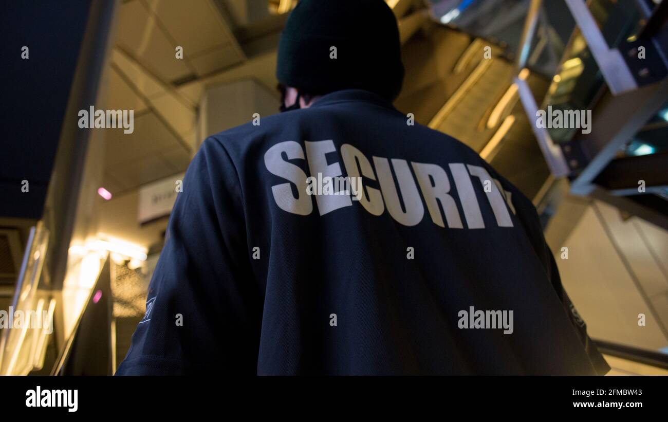 A rear view of a security guard walking through the street of the big ...