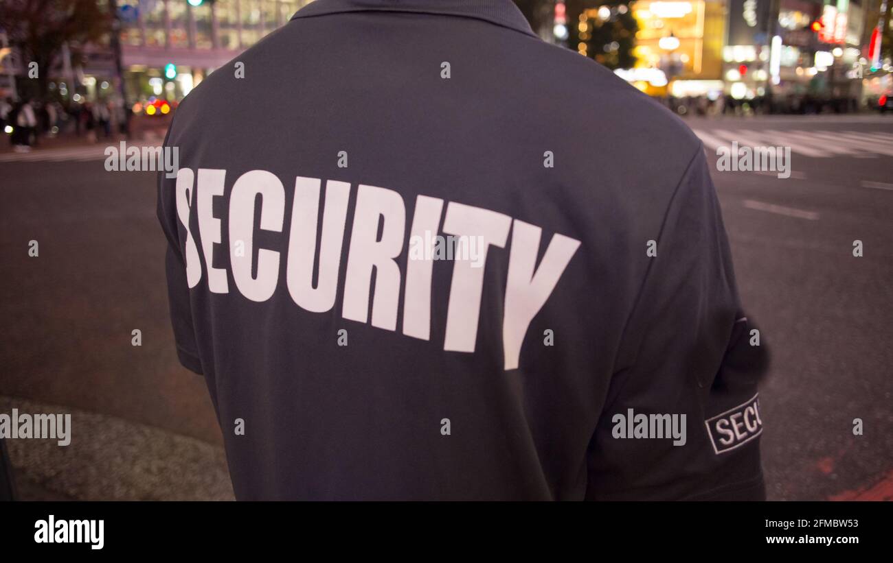 A rear view of a security guard walking through the street of the big ...