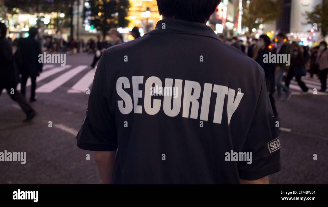A rear view of a security guard walking through the street of the big ...