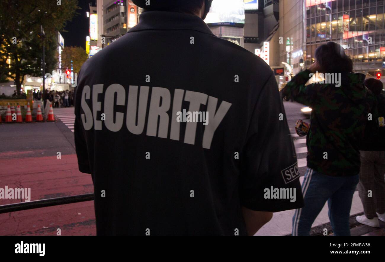 A rear view of a security guard walking through the street of the big ...