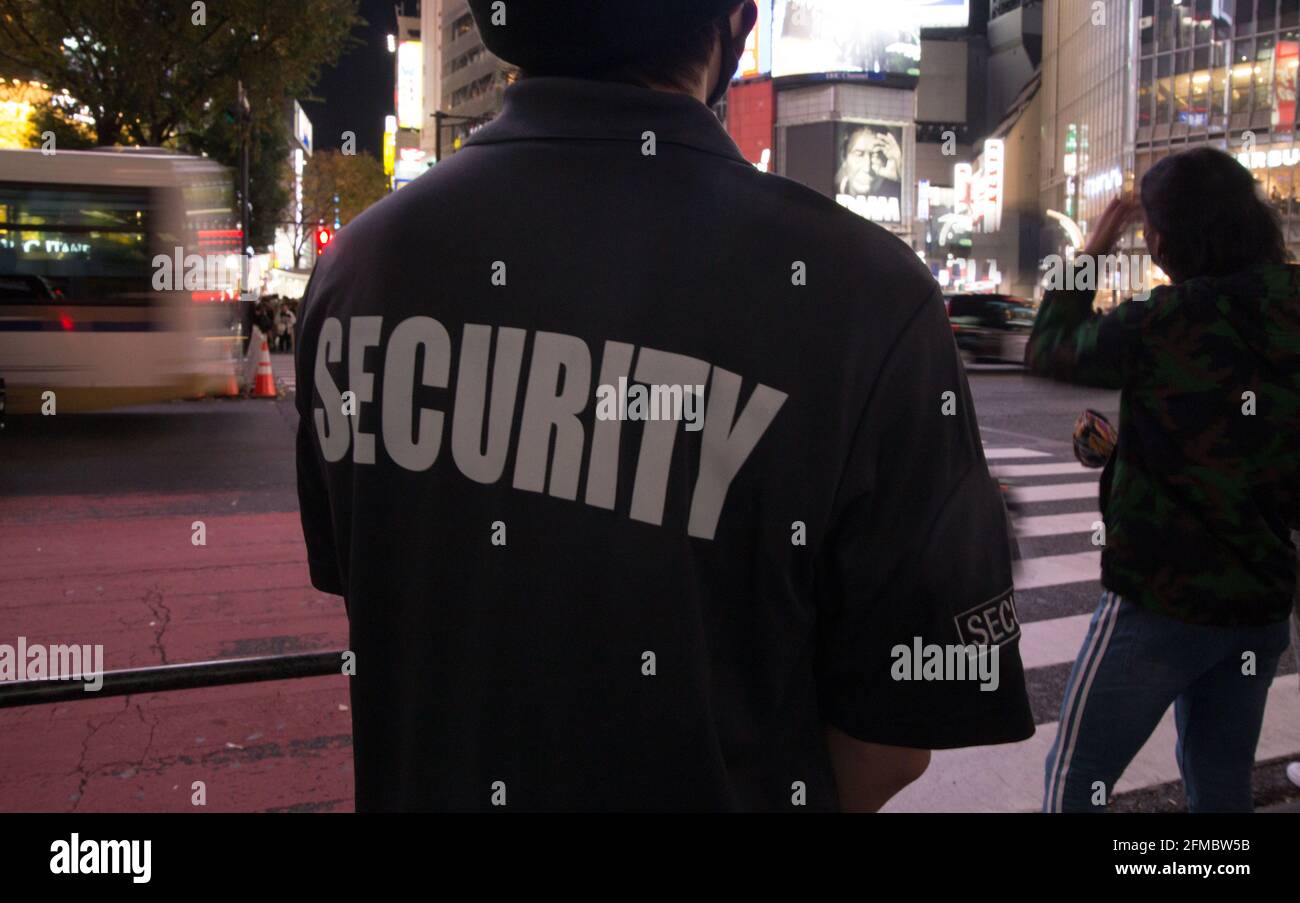 A rear view of a security guard walking through the street of the big ...