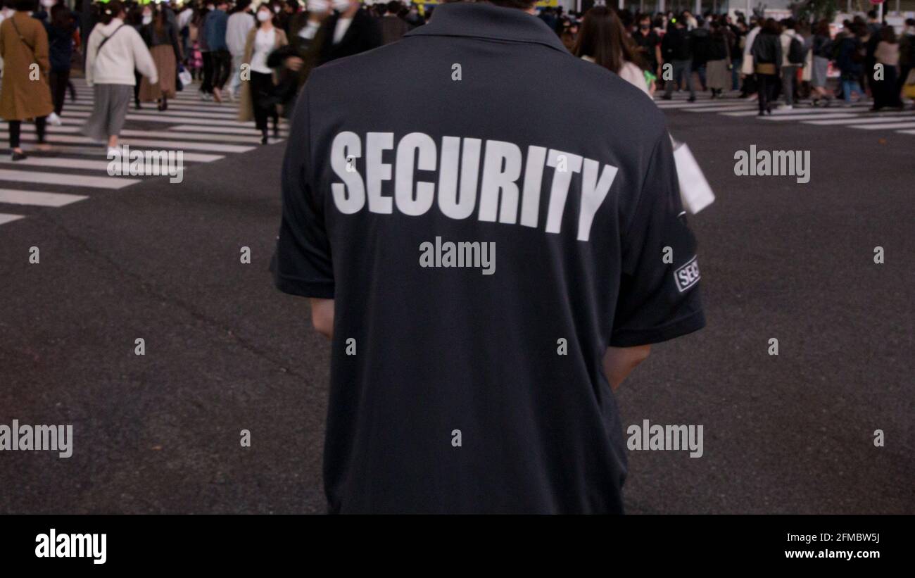 A rear view of a security guard walking through the street of the big ...