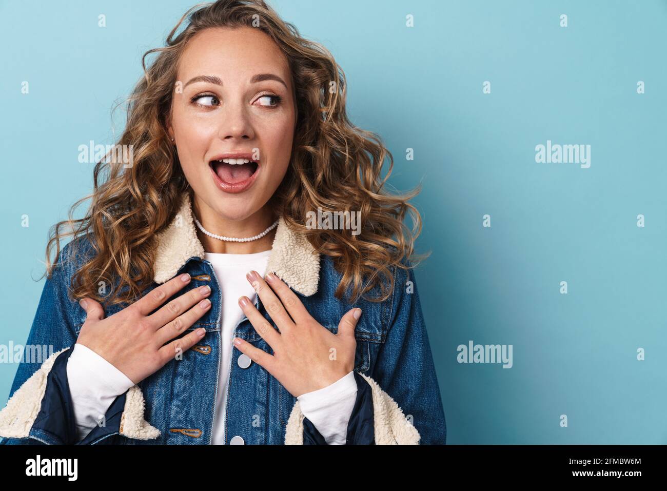 Blonde happy woman smiling and holding hands on her chest isolated over ...
