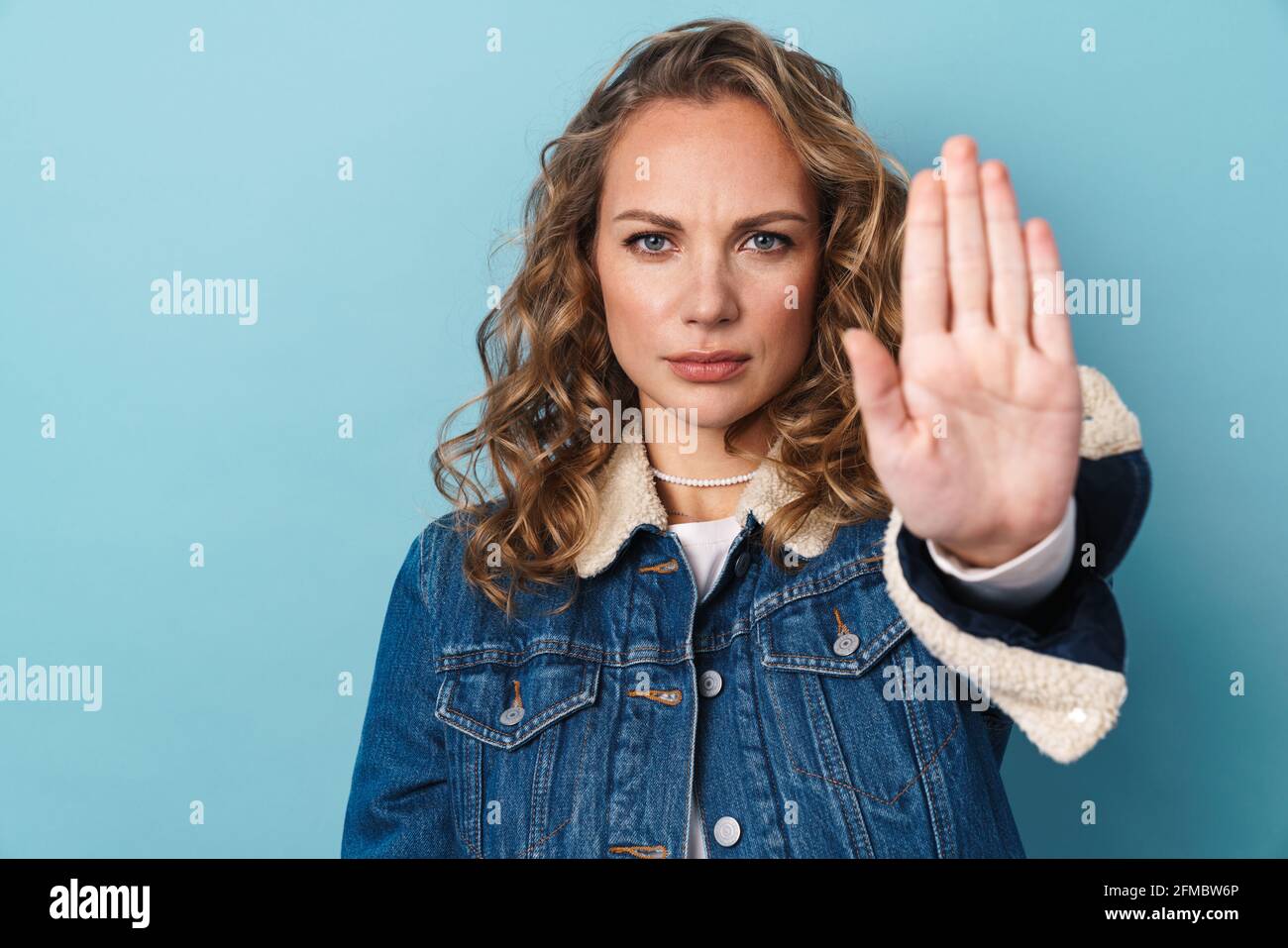 Blonde displeased woman showing stop gesture and looking at camera ...