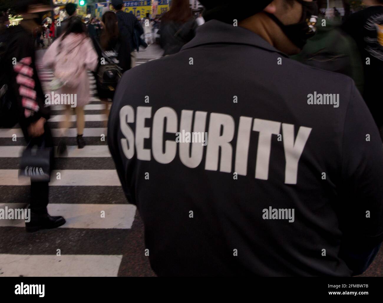 A rear view of a security guard walking through the street of the big ...