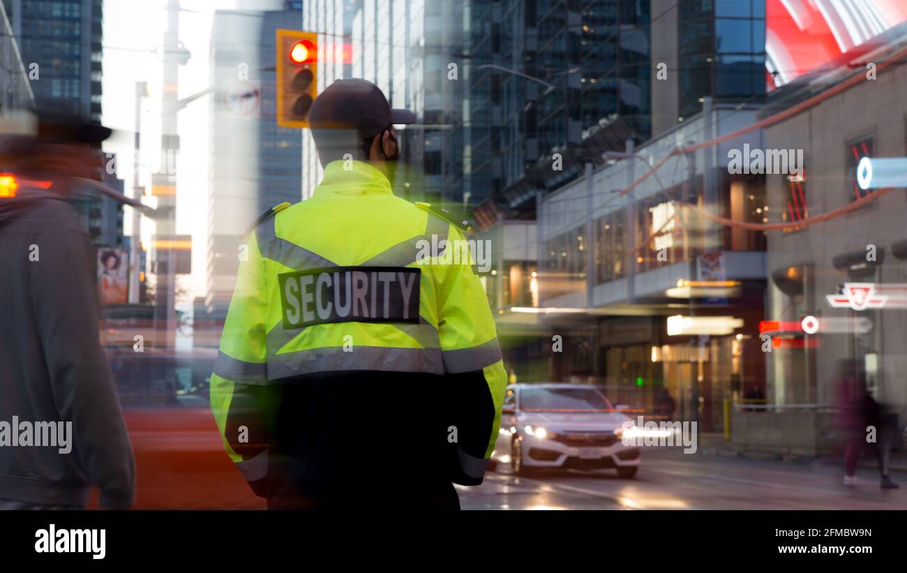 Traffic security guard in light green jacket patrolling street before ...