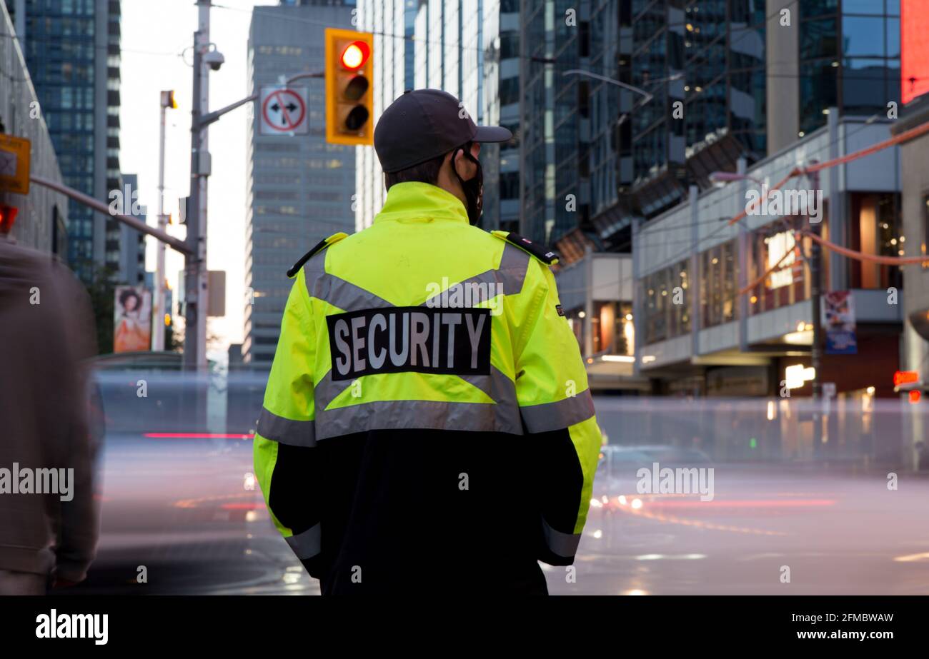 Traffic security guard in light green jacket patrolling street before ...