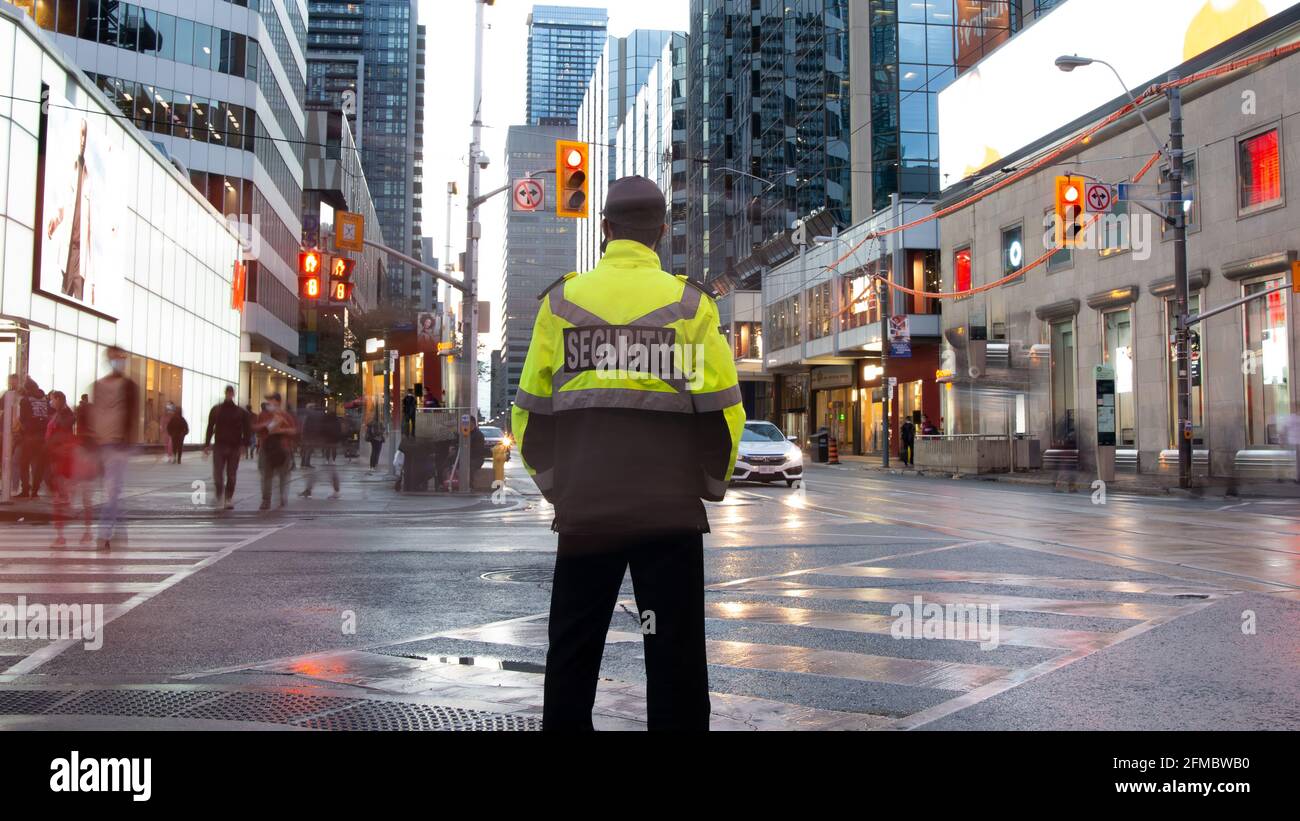Traffic security guard in light green jacket patrolling street before ...