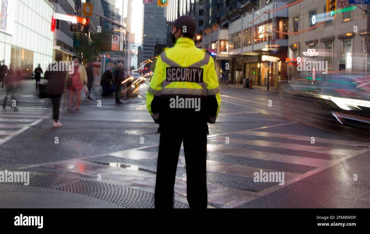 Traffic security guard in light green jacket patrolling street before ...