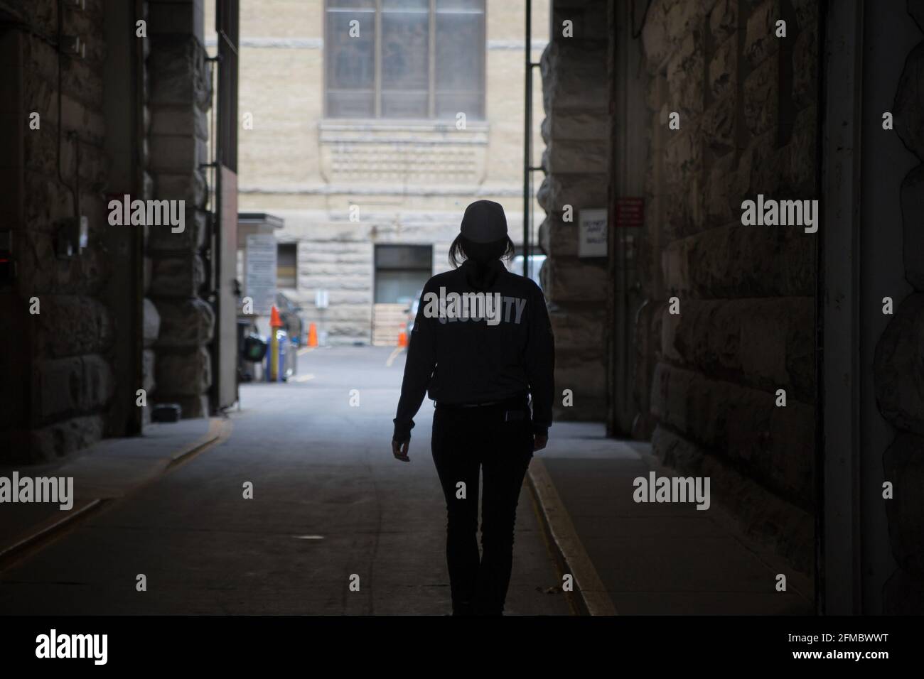 Black security guard in uniform patrolling a wide street in the daytime ...