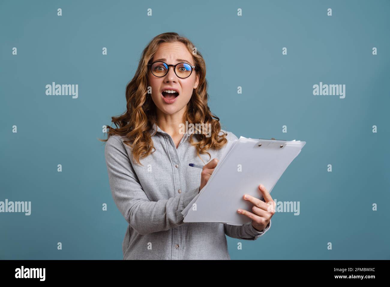 Shocked beautiful girl in eyeglasses writing down notes isolated over ...