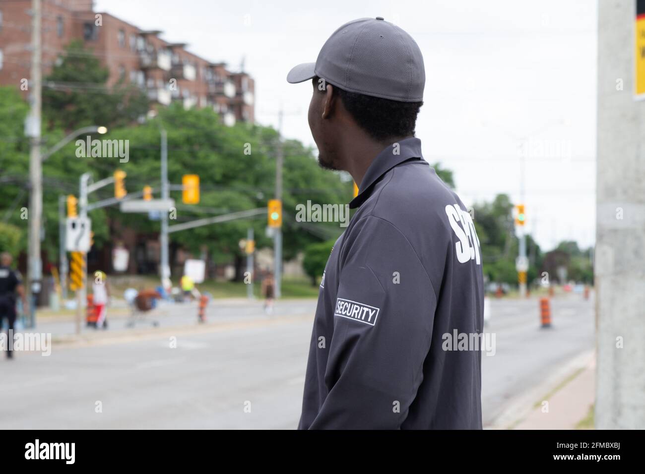 Tall black security guard in a grey uniform patrolling parking area in ...