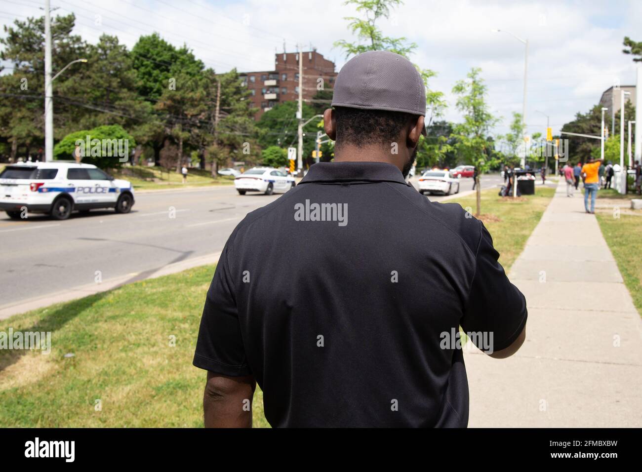 Black security guard in uniform patrolling a wide street in the daytime ...