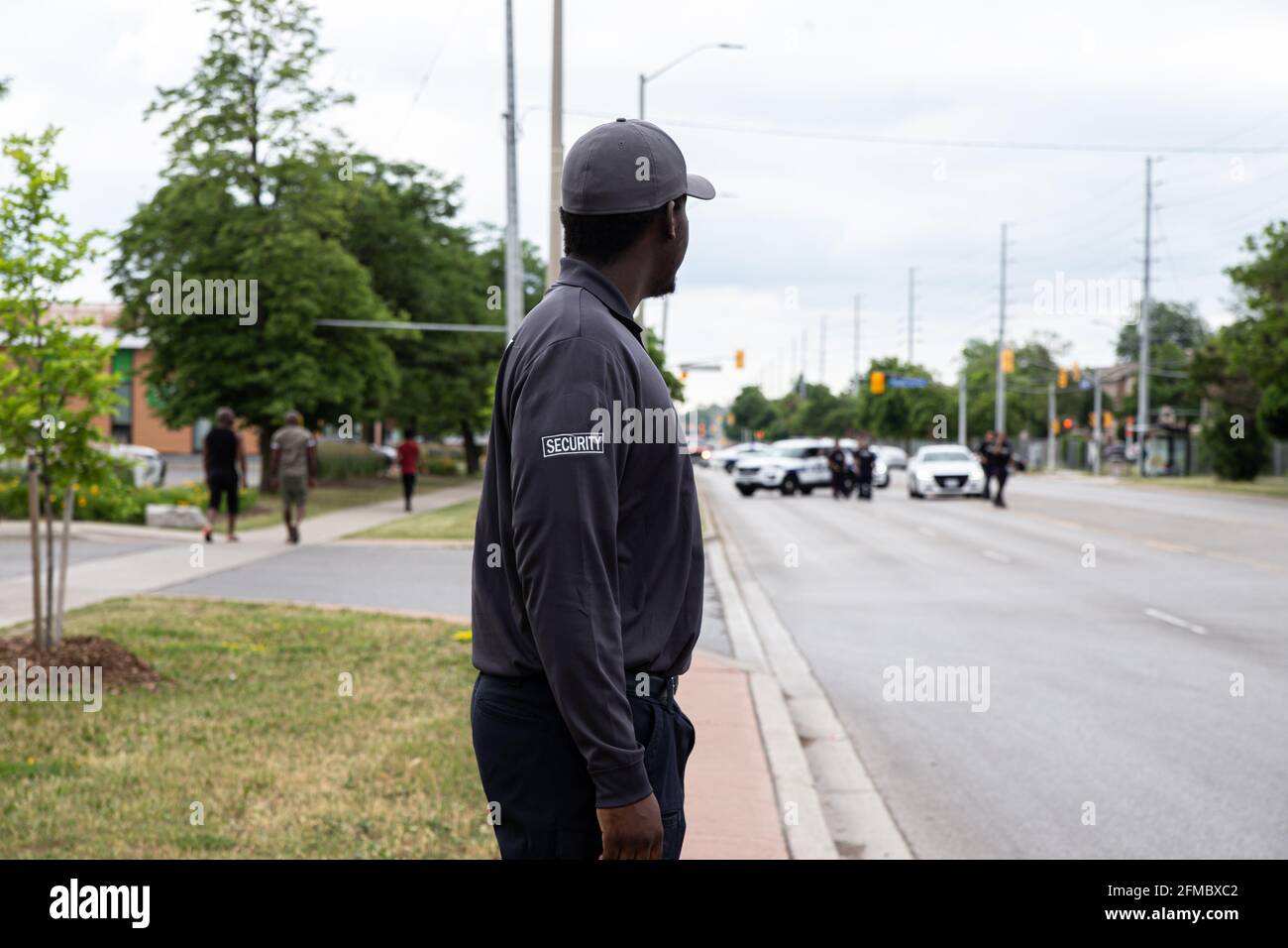 Black security guard in uniform patrolling a wide street in the daytime ...
