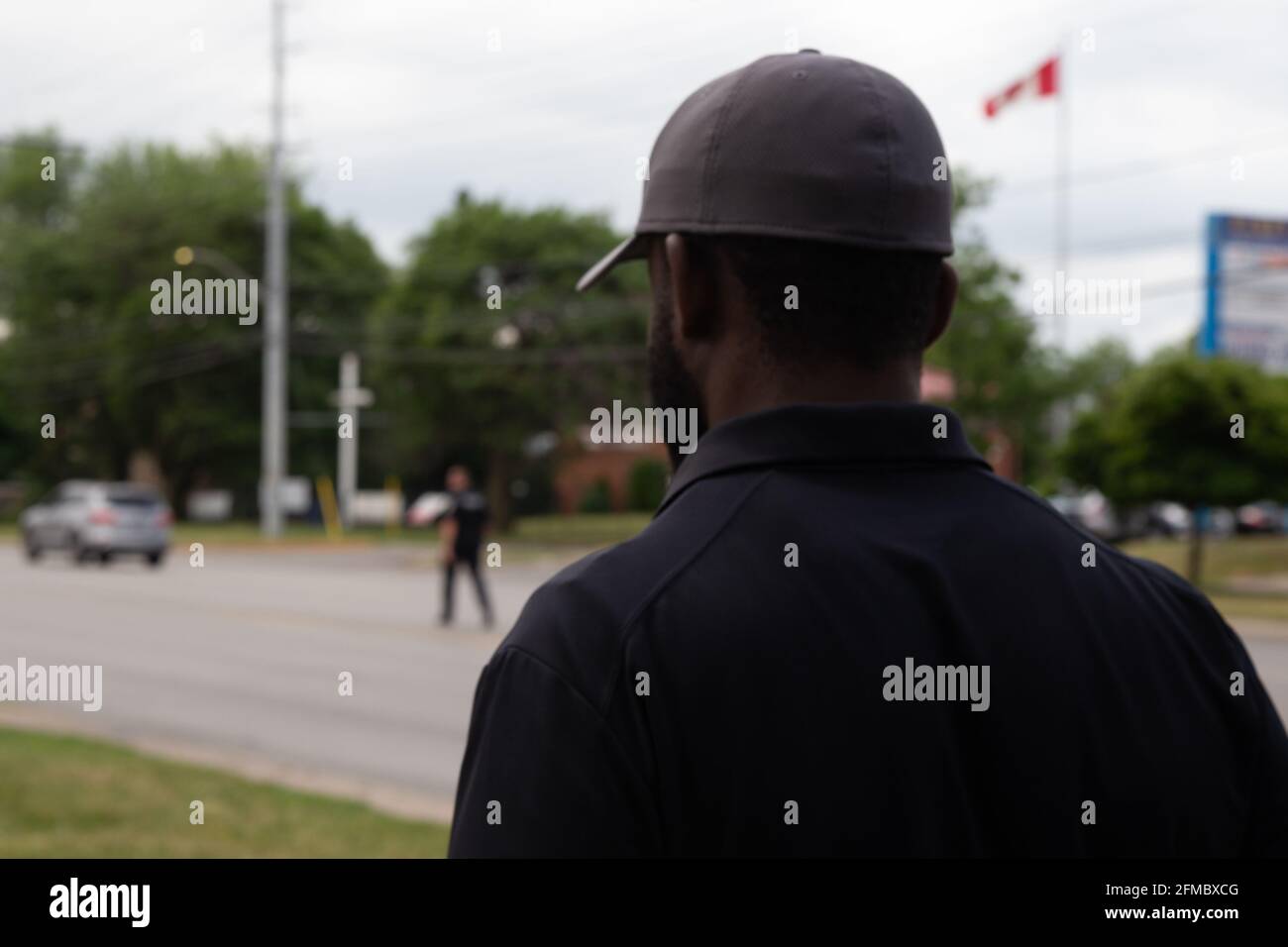 Black security guard in uniform patrolling wide street with police in ...
