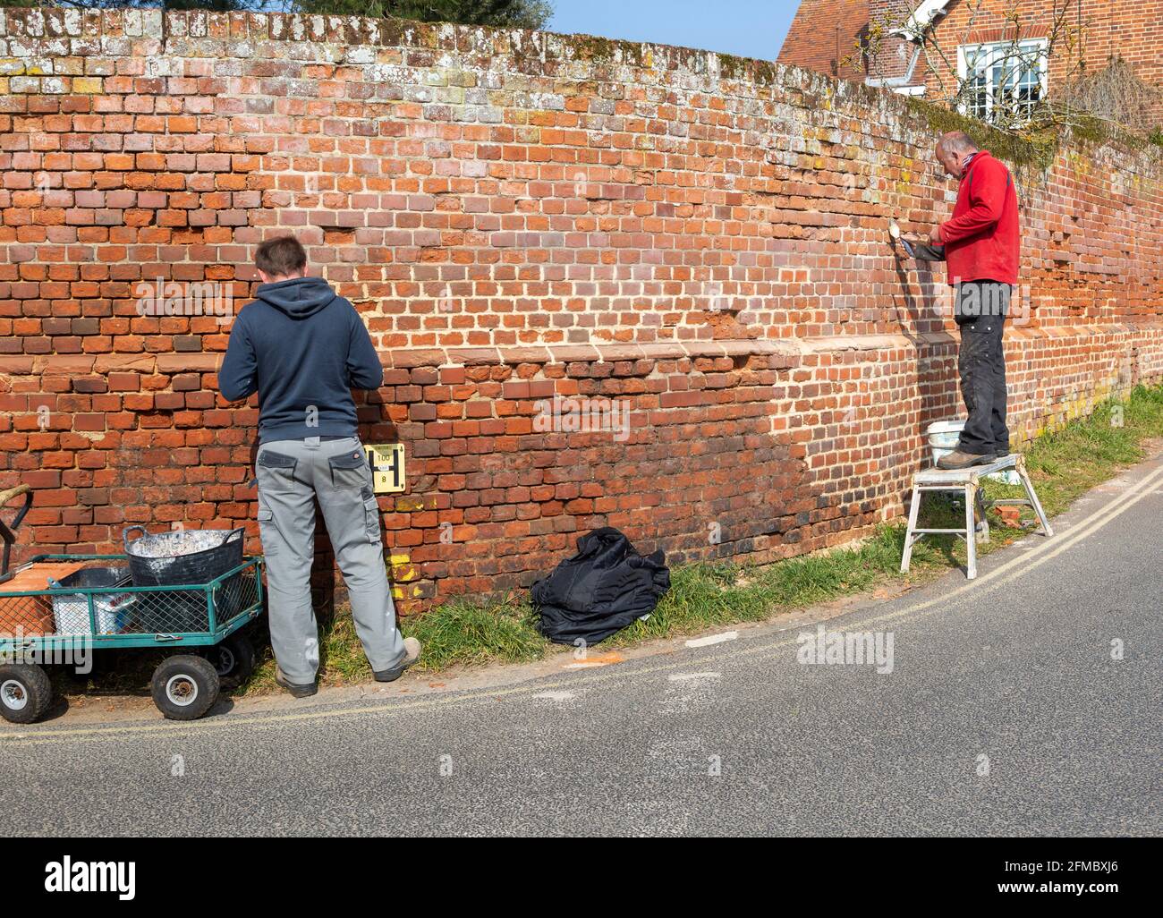 Two men repointing old red brick wall, Orford, Suffolk, England, UK ...