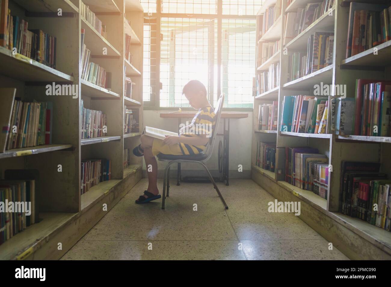 A boy reading a book in the library Stock Photo - Alamy