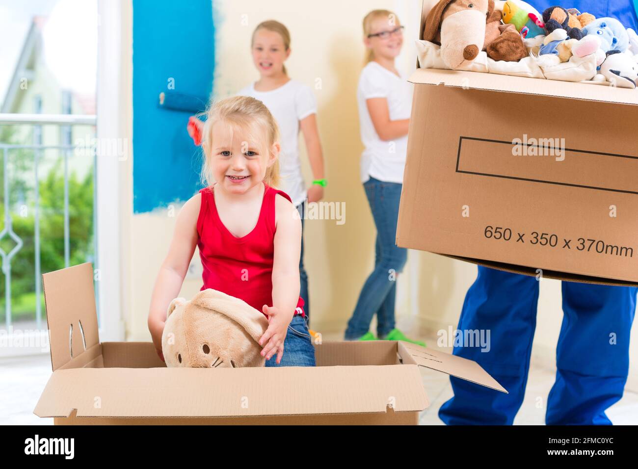 Family moving house with boxes full of stuff, they are painting the ...