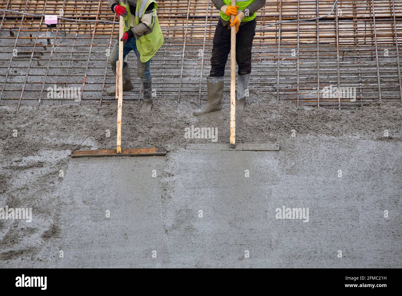Masons leveling fresh poured concrete at the building site Stock Photo ...