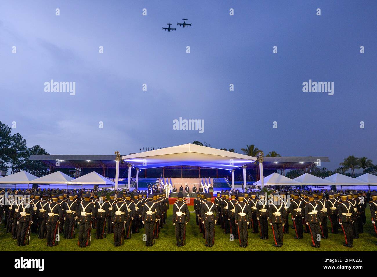 Dragonfly A-37 jets fly over a field with lined up soldiers at a ...