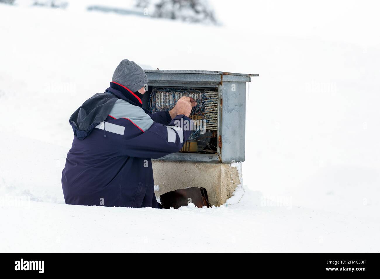 Technician working in the snow and repair telephone line, wiring ...