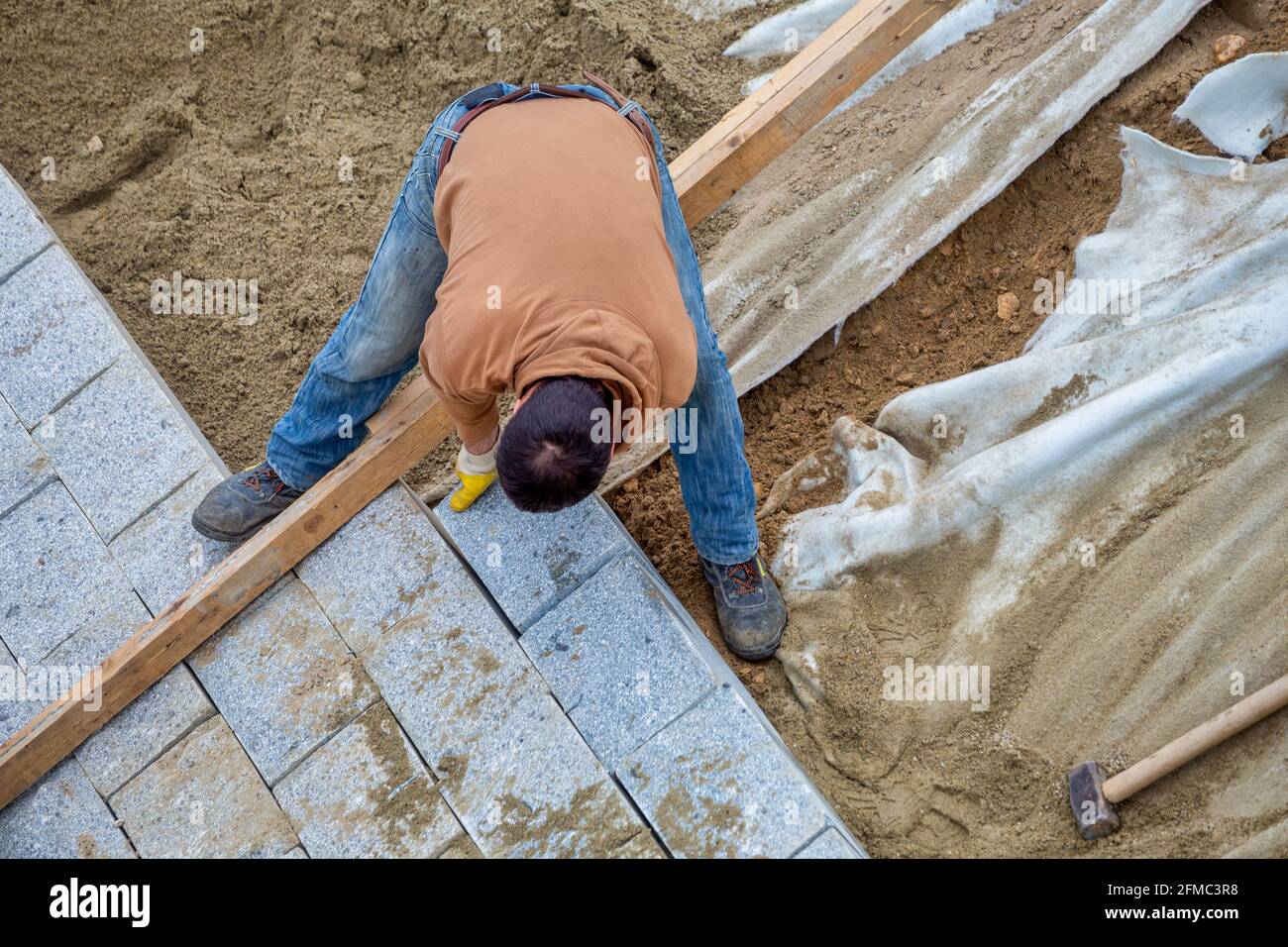 Worker strengthening river bank with granite stone Stock Photo - Alamy