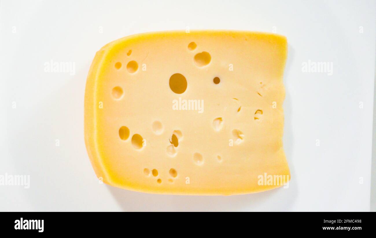 Flat lay. Slicing a large slice of gourmet cheese on a white background ...