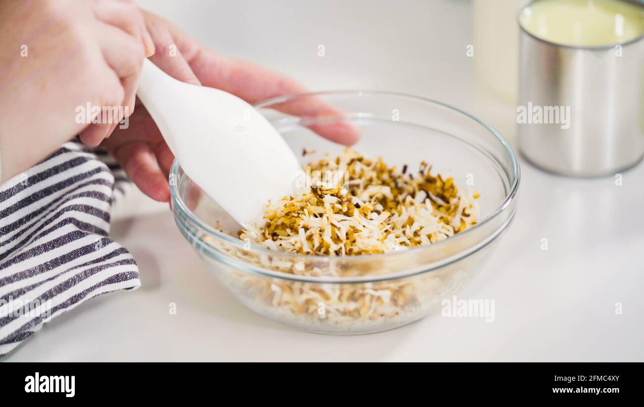Mixing ingredients in a glass mixing bowl to prepare homemade coconut ...
