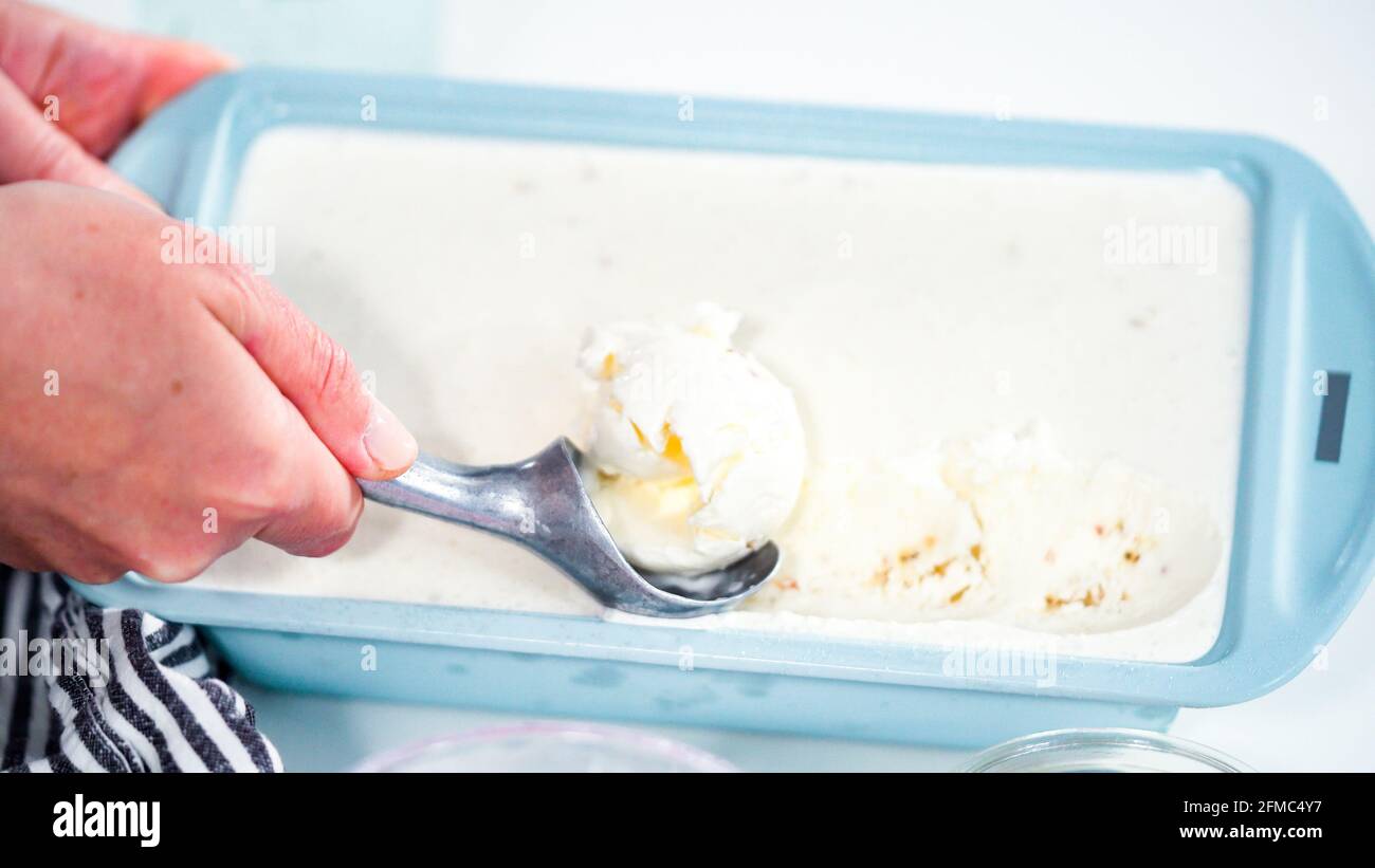 Scooping homemade coconut ice cream into a glass ice cream bowl Stock ...