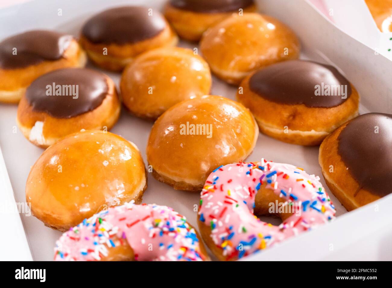 Variety of store-bought doughnuts in a white paper box Stock Photo - Alamy