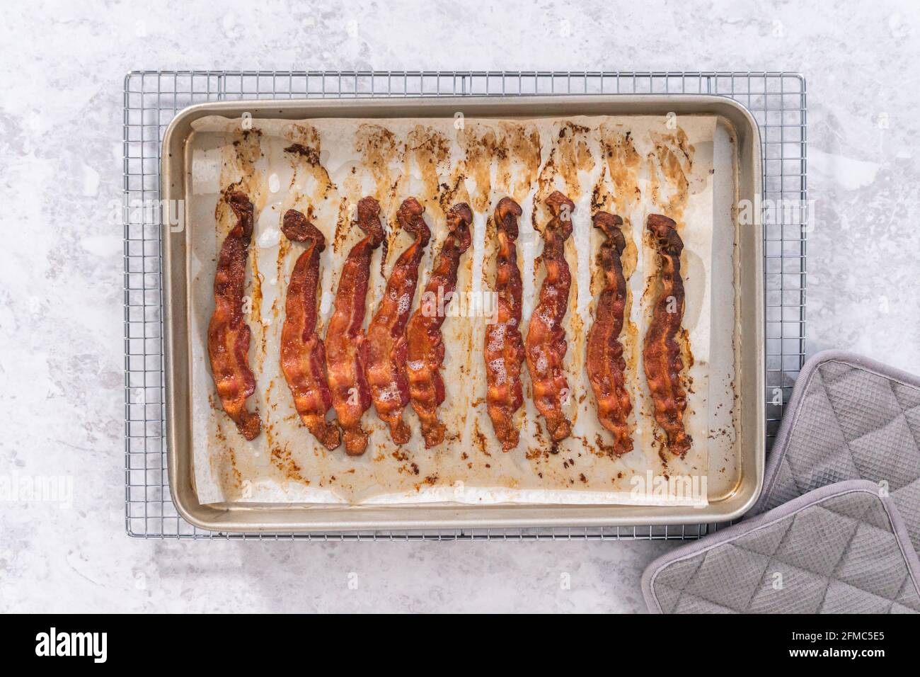 Flat lay. Cooked bacon strips on a baking sheet with white parchment ...