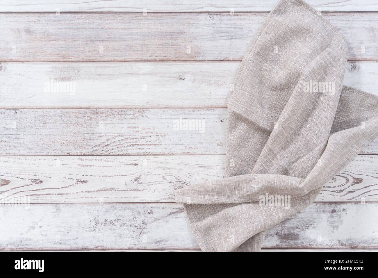 Flat lay. Folding a natural color linen dinner napkin on a white wooden ...