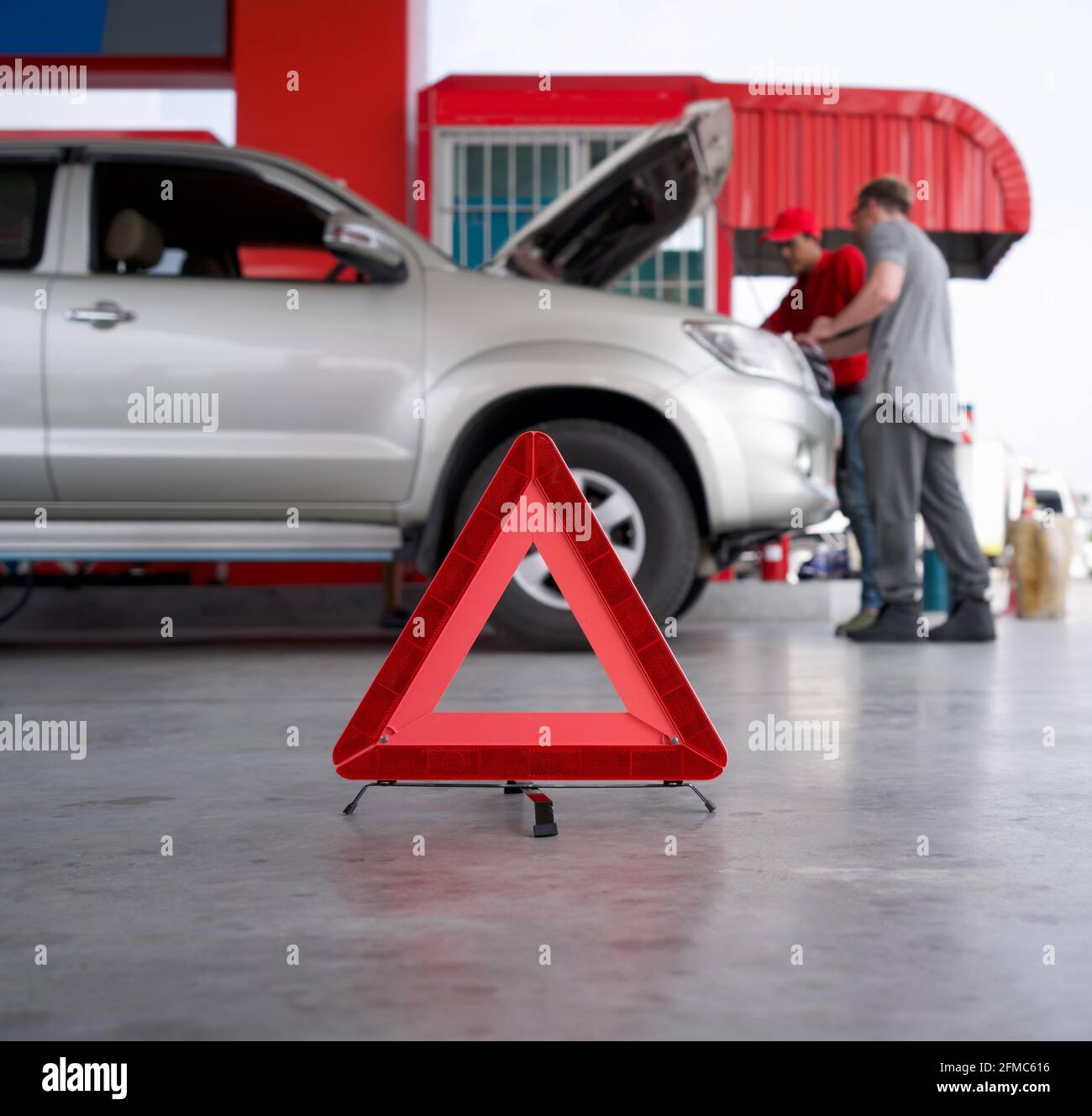 Red triangle reflector roadside warning on the floor. There is a broken ...