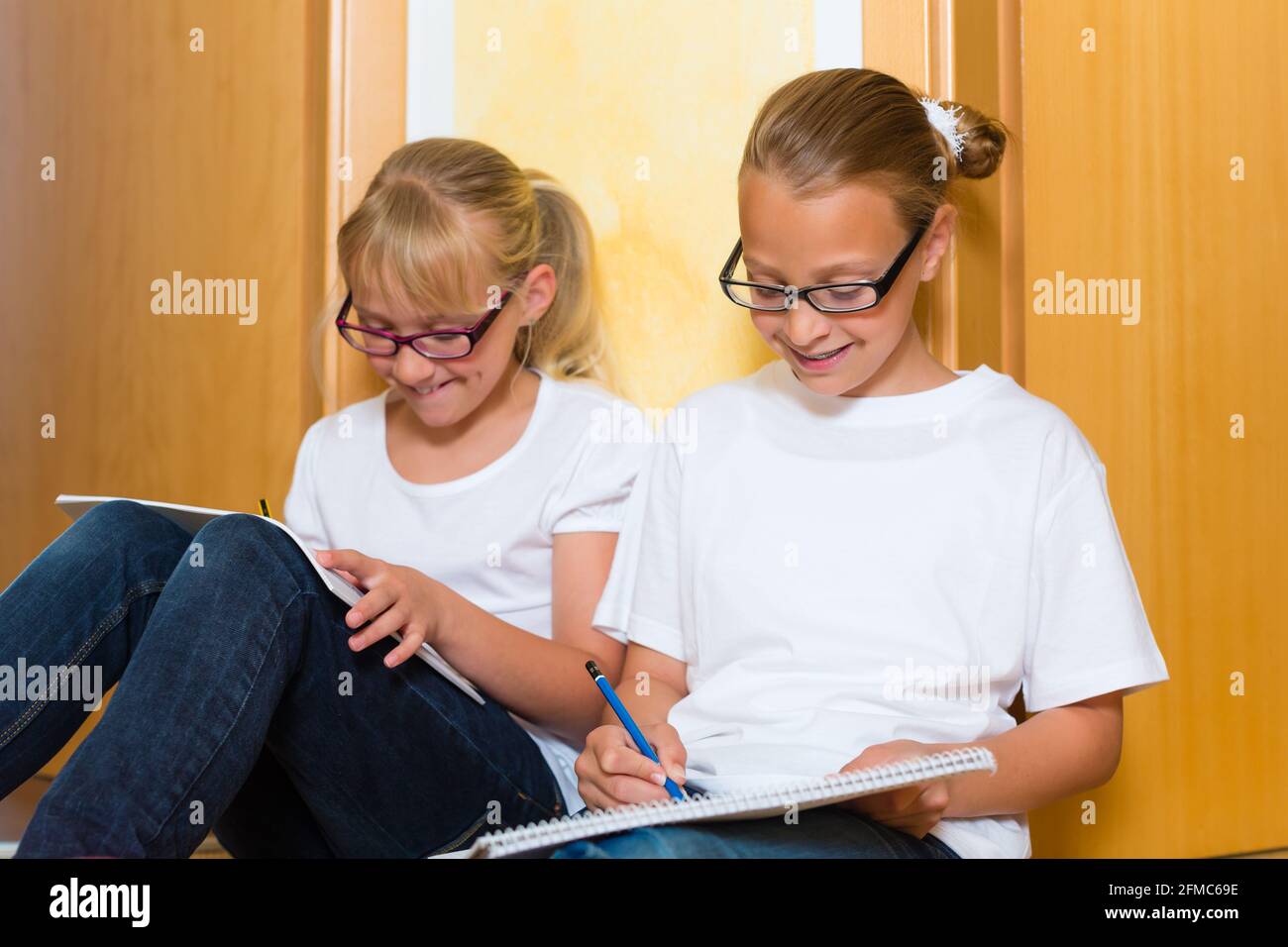 Girls or Sisters doing homework together at home for school next day ...