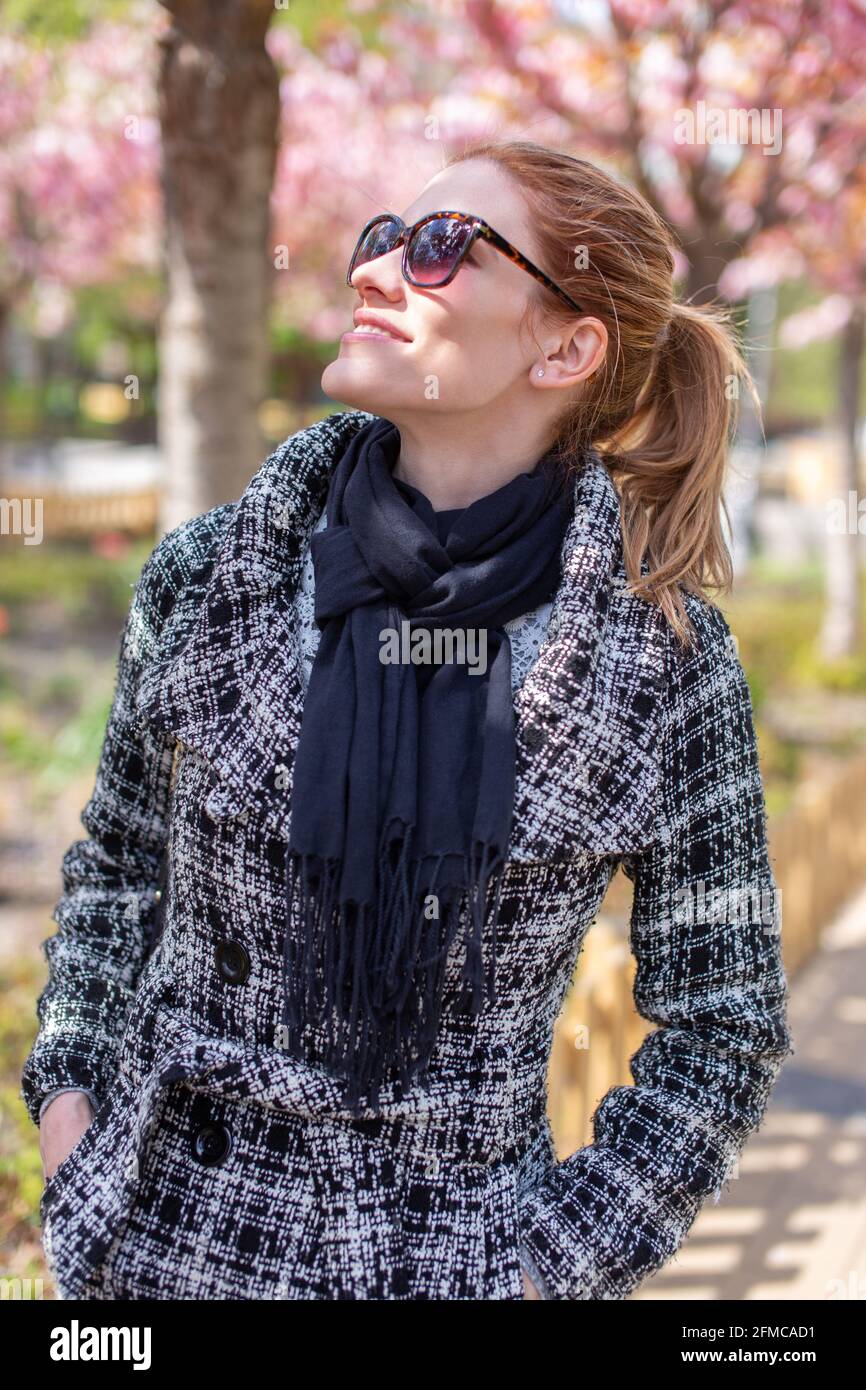 Young positive Caucasian woman enjoying walking and sunshine at public ...