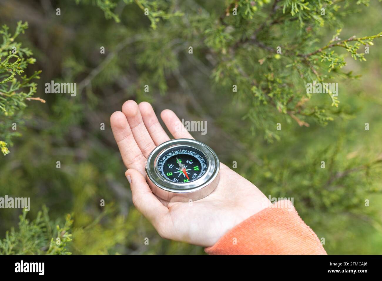 hand holding a compass to orient yourself in the middle of the mountain ...