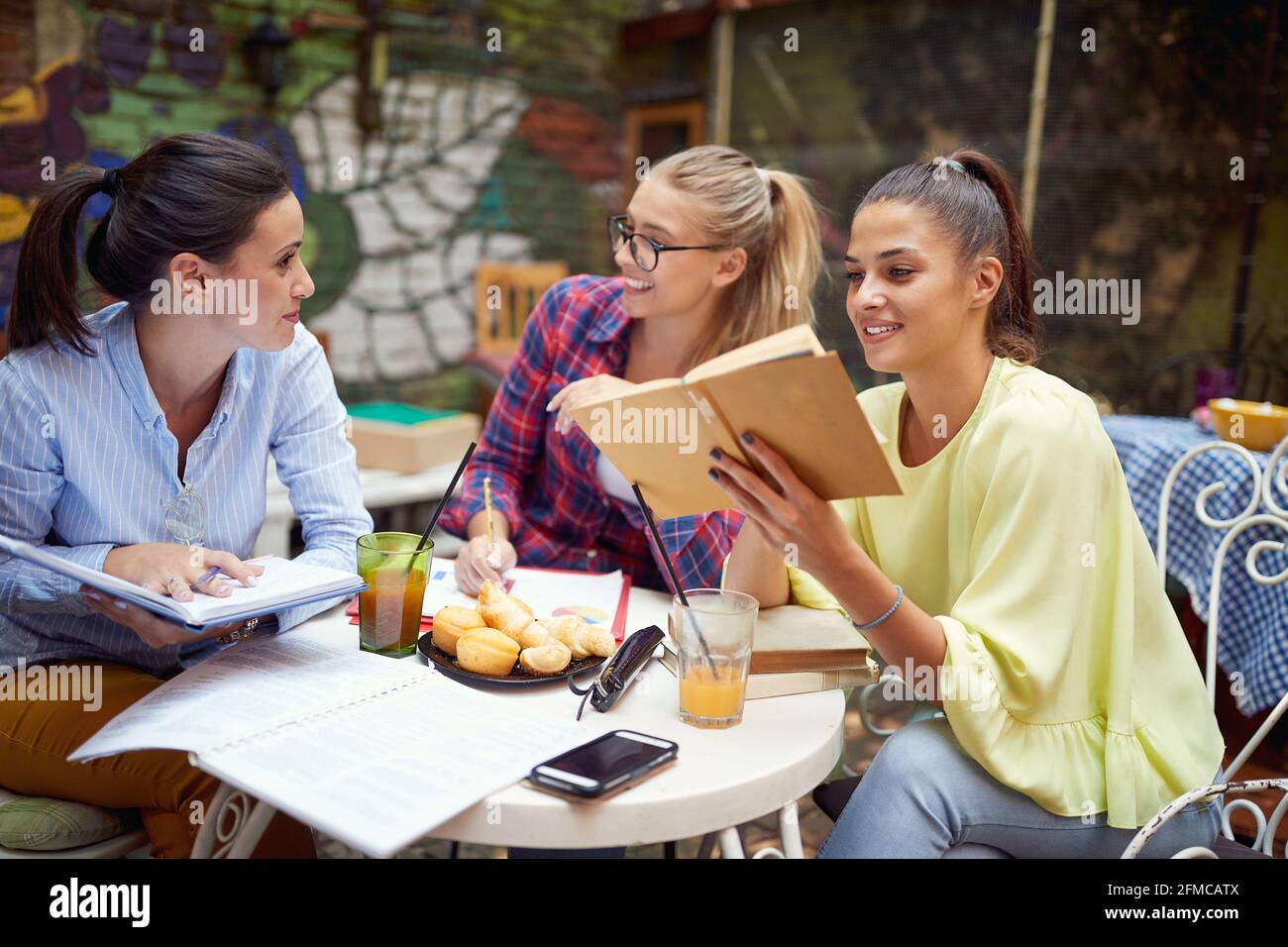 A group of female students doing university tasks while sitting and ...