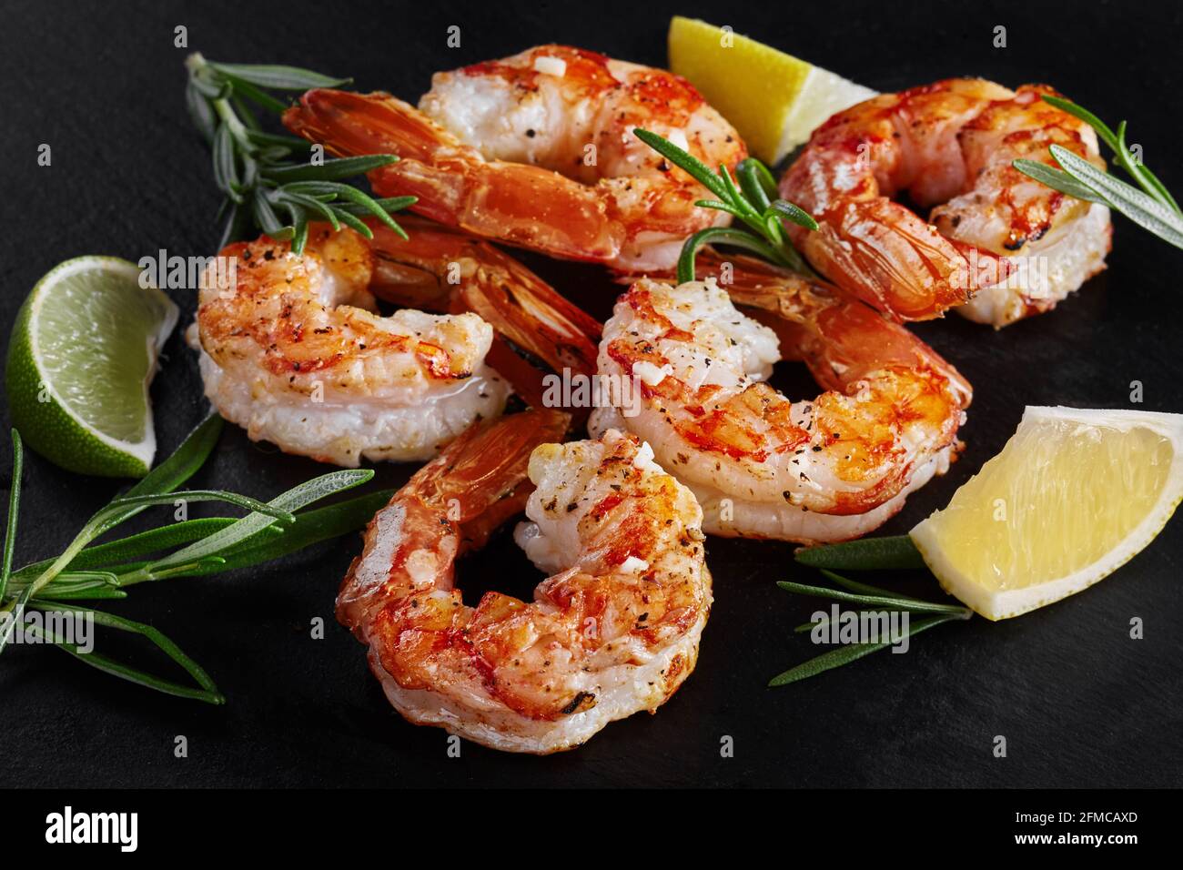 Grilled prawn tails with lemon and rosemary on black background Stock ...