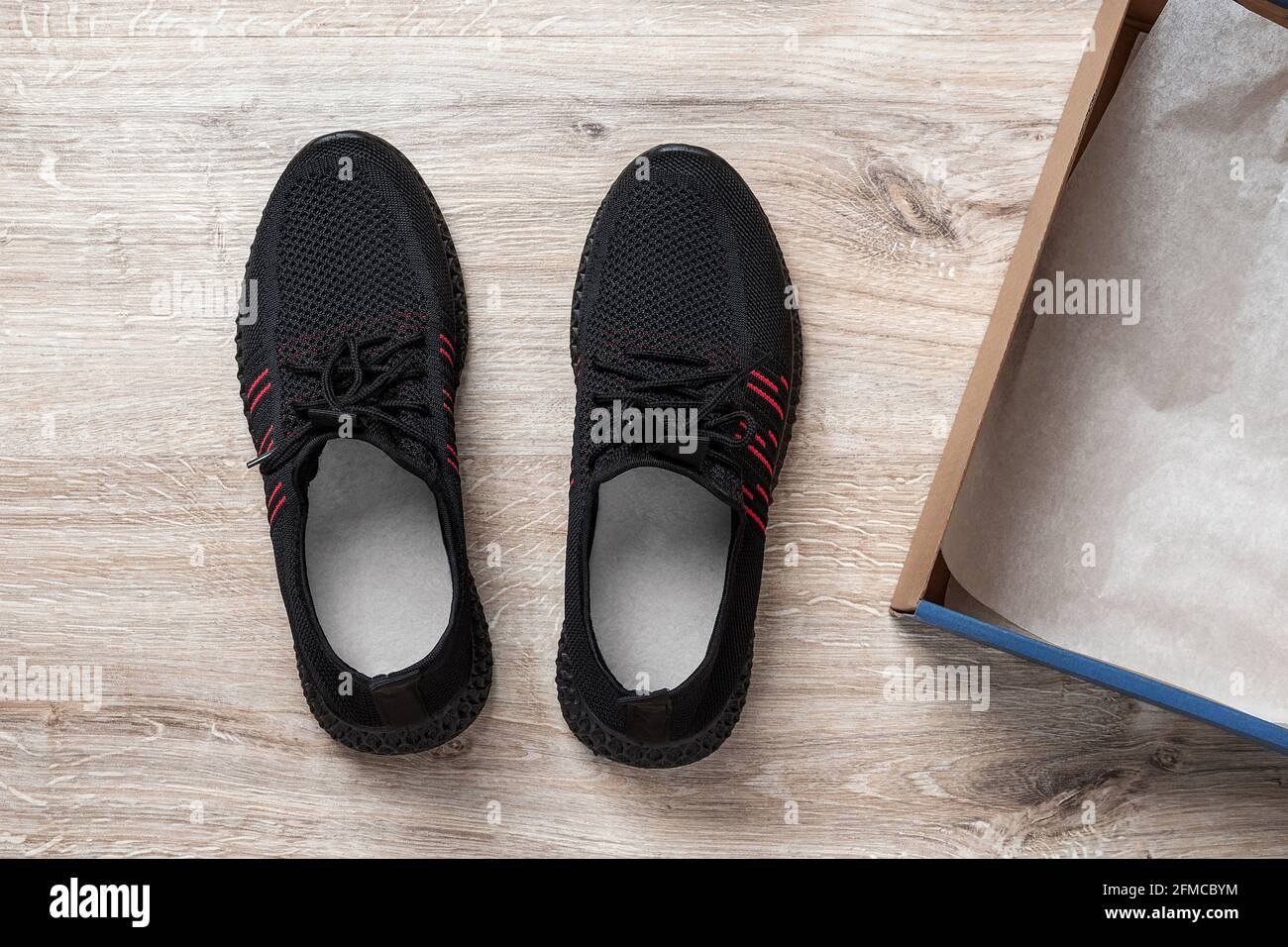 Black mesh sneakers near brown cardboard box on the floor. Open box ...