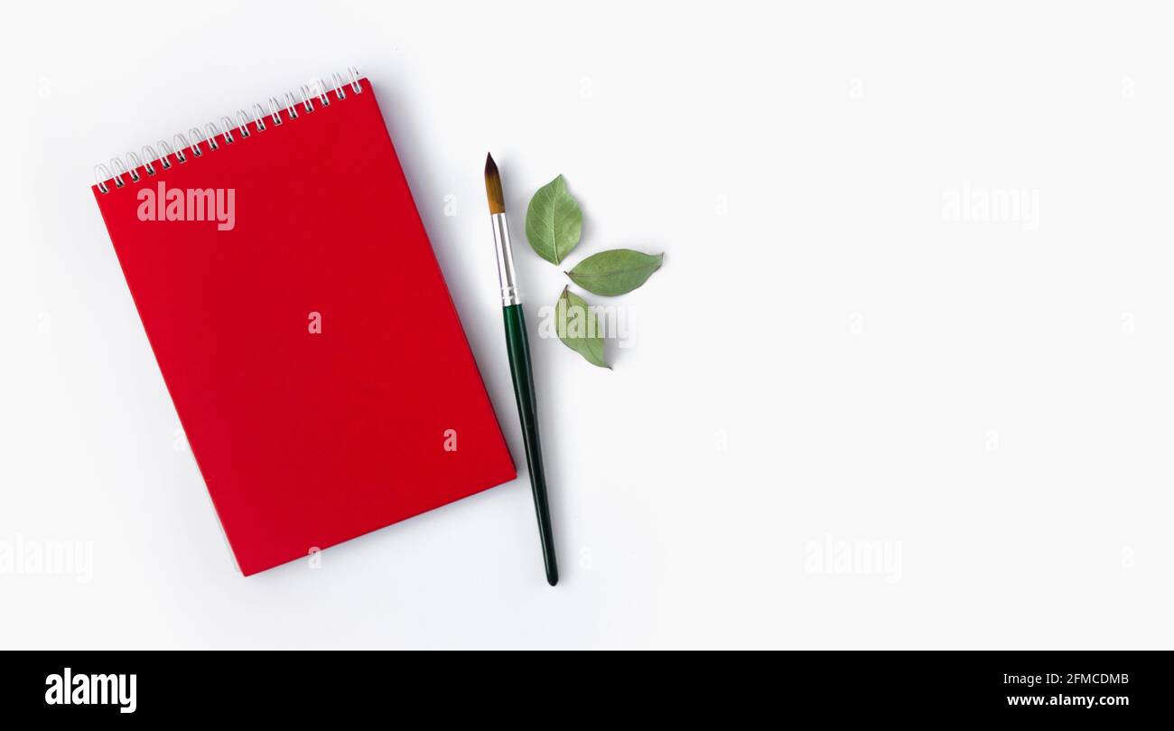 Red notepad with a paintbrush on a white background. Top view, layout ...