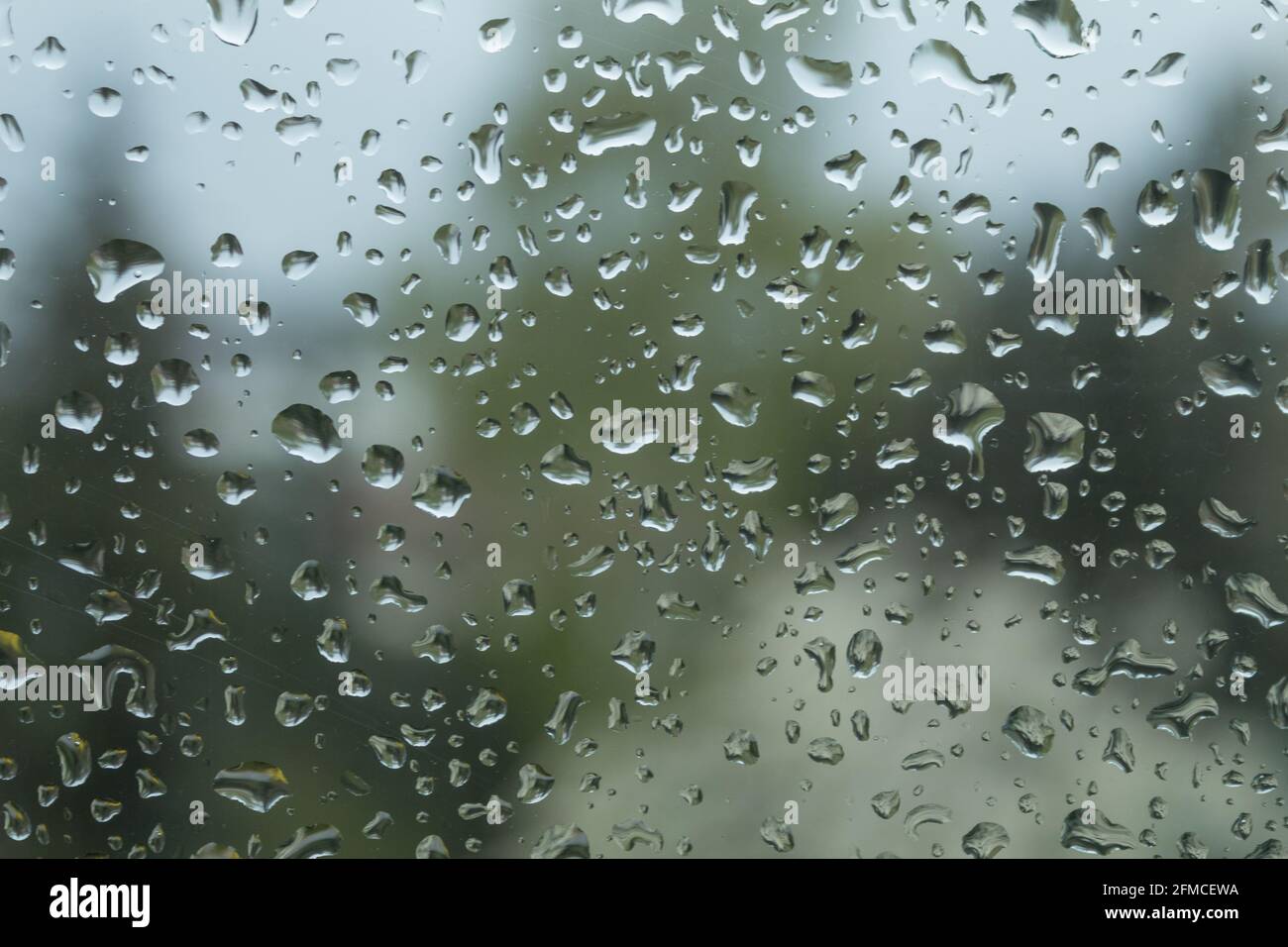 Raindrops on the window, wet surface. Rain view from the house, through ...